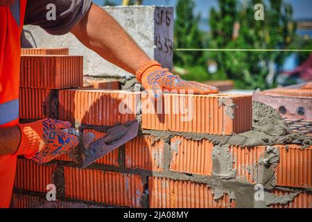 Close up of bricklaying industrial installing bricks on construction ...