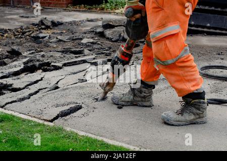 Construction worker breaking road gully using hydraulic breacker during ...