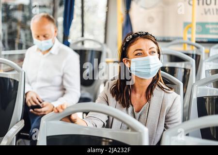 Travelers wearing protective masks commuting by public bus Stock Photo - Alamy