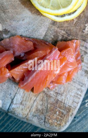 sliced red salted salmon during cooking, cutting fish fillets during ...