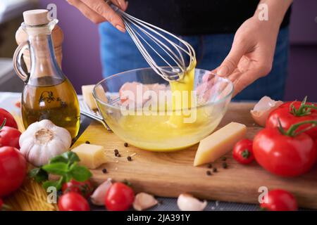 Woman beating egg yolks with a whisk making homemade pasta carbonara ...