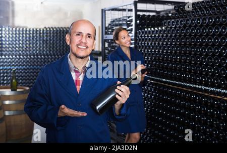 happy mature man winery worker looking at glass of red wine on ...