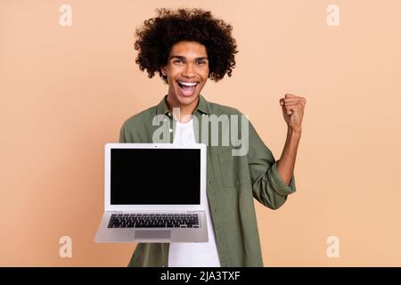 Portrait of attractive cheerful lucky wavy-haired guy using laptop ...