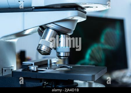 Specialist analyzing dna on microscope in laboratory, wearing face mask ...