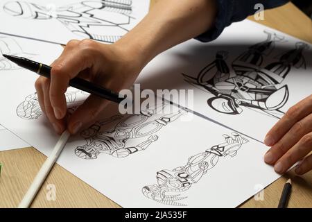 The illustrator draws sketches of robot computer game characters. The ...