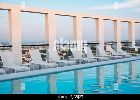 sunbathers line a rooftop pool on a modern apartment in the city of ...
