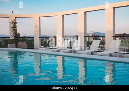 sunbathers line a rooftop pool on a modern apartment in the city of ...