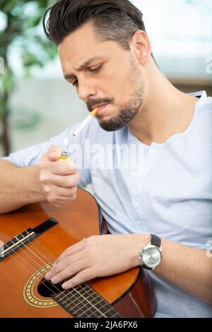 male guitarist lighting a cigarette Stock Photo - Alamy