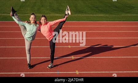Happy teenage gymnasts do vertical splits holding legs at athletics ...