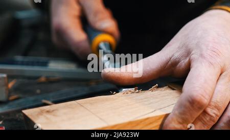 Carpentry - a woodworker cutting out the recess on the wooden block ...