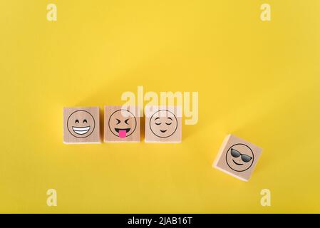 Icons of different smiley faces on wooden cubes with a yellow ...