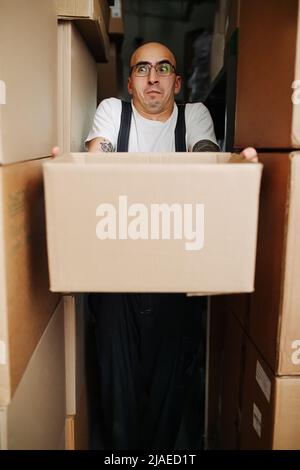 A man is carrying a big stack of cardboard boxes in his arms Stock ...