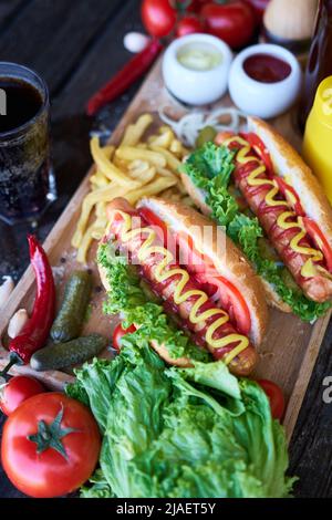 BBQ hot dog served with vegetables and French fries and sauces on ...