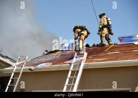 SDFD Firefighters working on the roof to get to remaining flames at a ...