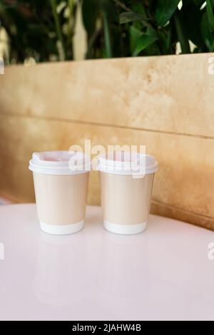 A man walks with two cups of coffee past solar panels set up on the ...