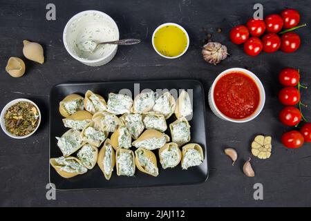 Stuffed conchiglie preparation, creamy ricotta and tomatoes sauce, top ...