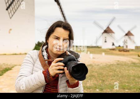 Woman tourist takes pictures of the windmills of Mota del cuervo. Spain ...