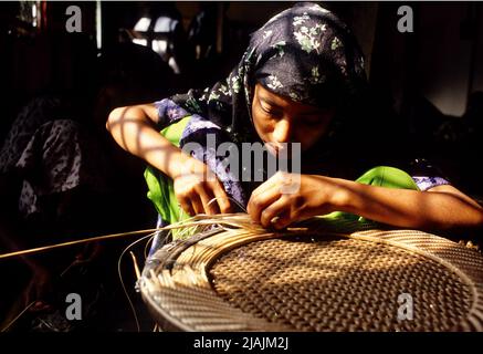 Rural woman weaving a sitting stool (mora) with bamboo. Netrokona ...