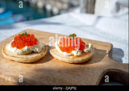 Two small starters blinis with sour cream and salted salmon red caviar ...