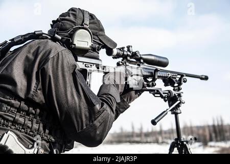 Sniper aiming with telescopic optical sight on sniper rifle mounted on ...