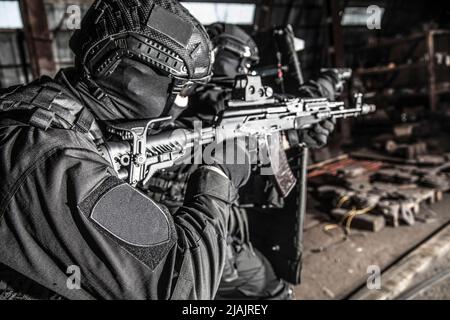 Police special reaction team aiming guns while moving forward under ...