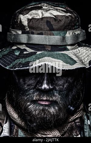 Bearded commando soldier with camouflage face paint, wearing a tactical ...