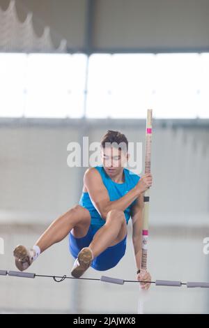 Pole vaulting indoors - young man jumping over the partition Stock ...