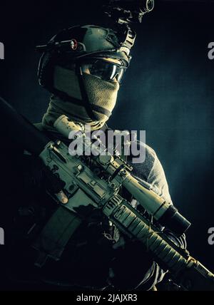 Sniper wearing face mask and helmet with thermal imager, holding rifle ...