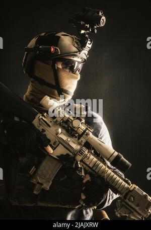 Sniper wearing face mask and helmet with thermal imager, holding rifle ...