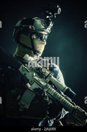 Sniper wearing face mask and helmet with thermal imager, holding rifle ...