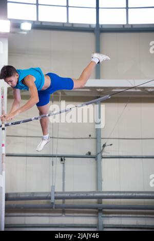 Pole vaulting indoors - young man jumping over the partition Stock ...