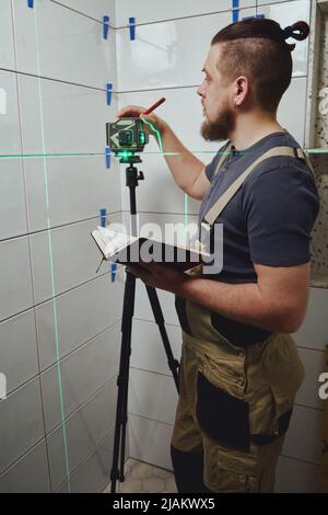 Tiler checks tile laying with building measuring laser level Stock ...