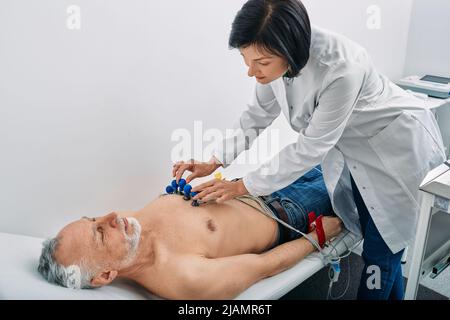 Cardiologist installing vacuum sensors on male child chest during ...