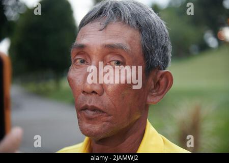 Portrait of an elderly Malay man with piercing blue eyes looking ...