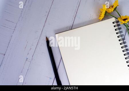 Note book flat lay with sunflowers on wooden desk. Directly above. Copy ...