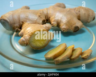 Cut ginger root on a transparent plate. Blue background Stock Photo - Alamy