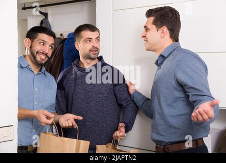 Two smiling men coming to visit their friend at home Stock Photo - Alamy