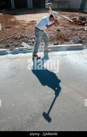 using Bobcat and hand sledge sledgehammers to level and clean dirt site ...