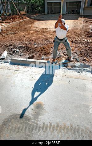 using Bobcat and hand sledge sledgehammers to level and clean dirt site ...