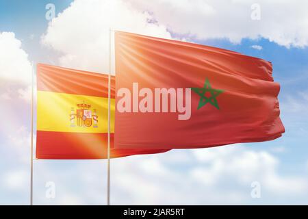 Morocco and Spain flags waving together on blue cloudy sky, two country ...