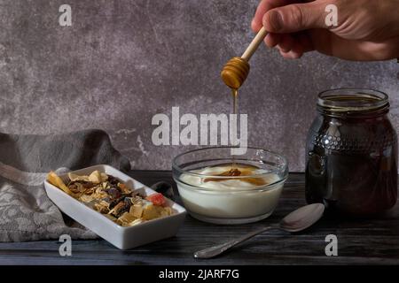 A person's hand pouring natural honey over freshly made homemade yogurt ...