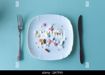 A handful of pills, capsules and multi-colored tablets on a plate next ...