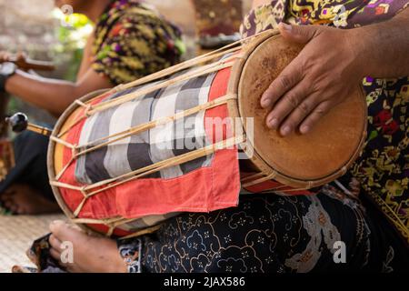 A musician plays a kendhang or ketipung, a traditional Balinese ...