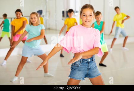 Happy tween girl dancing during group class in choreographic studio ...
