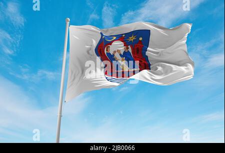 official flag of Aarhus , Denmark at cloudy sky background on sunset ...