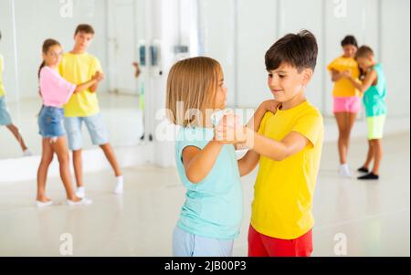 Tween boy and girl practicing slow pair dancing during group class ...
