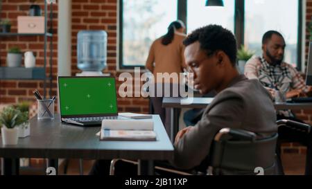 Company employee analyzing greenscreen on laptop, working in disability ...