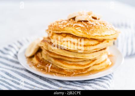 Stack of freshly baked coconut banana pancakes garnished with sliced ...