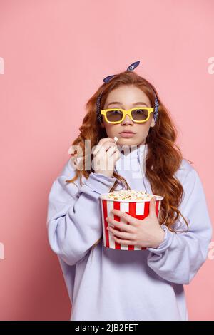 Redhead young woman eating popcorn using tv control depressed and worry ...