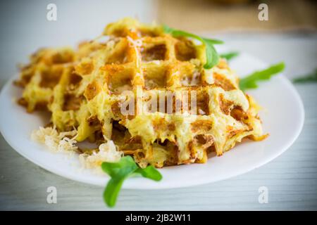 fried potato waffles with cheese in a plate on a light wooden table ...